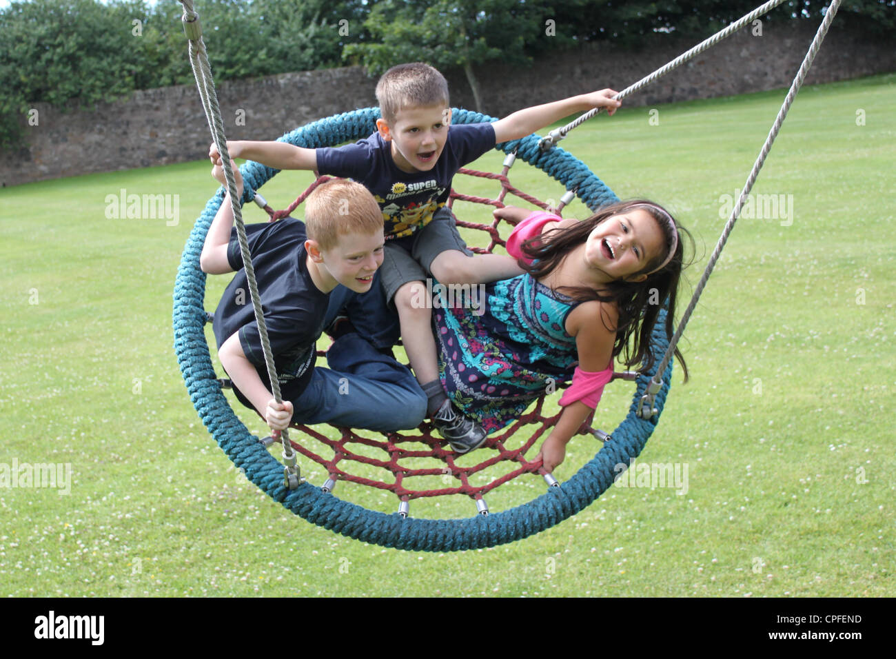 Three children having fun on swing Stock Photo - Alamy