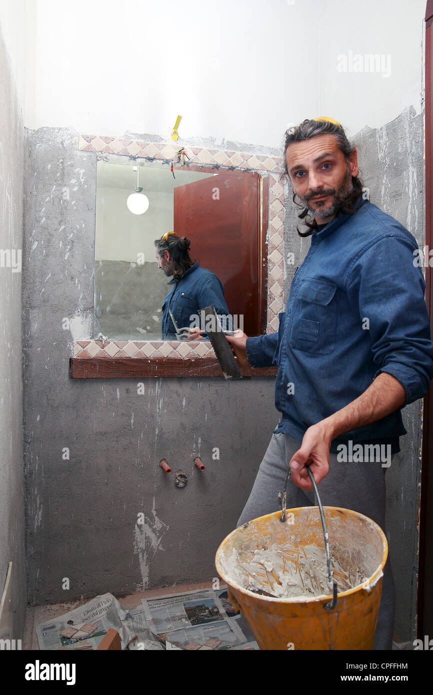 Tiler poses in a bathroom installing ceramic tiles Stock Photo - Alamy