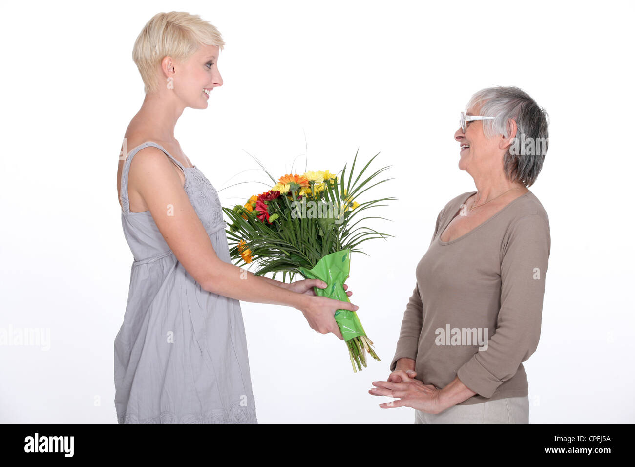 Young woman offering a bouquet of flowers to her grandmother Stock ...