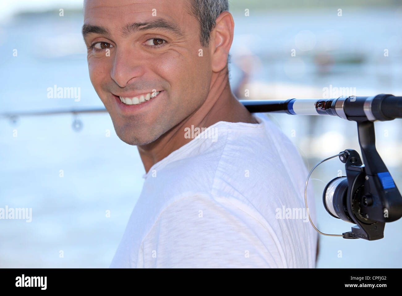 Man with fishing rod over his shoulder Stock Photo - Alamy