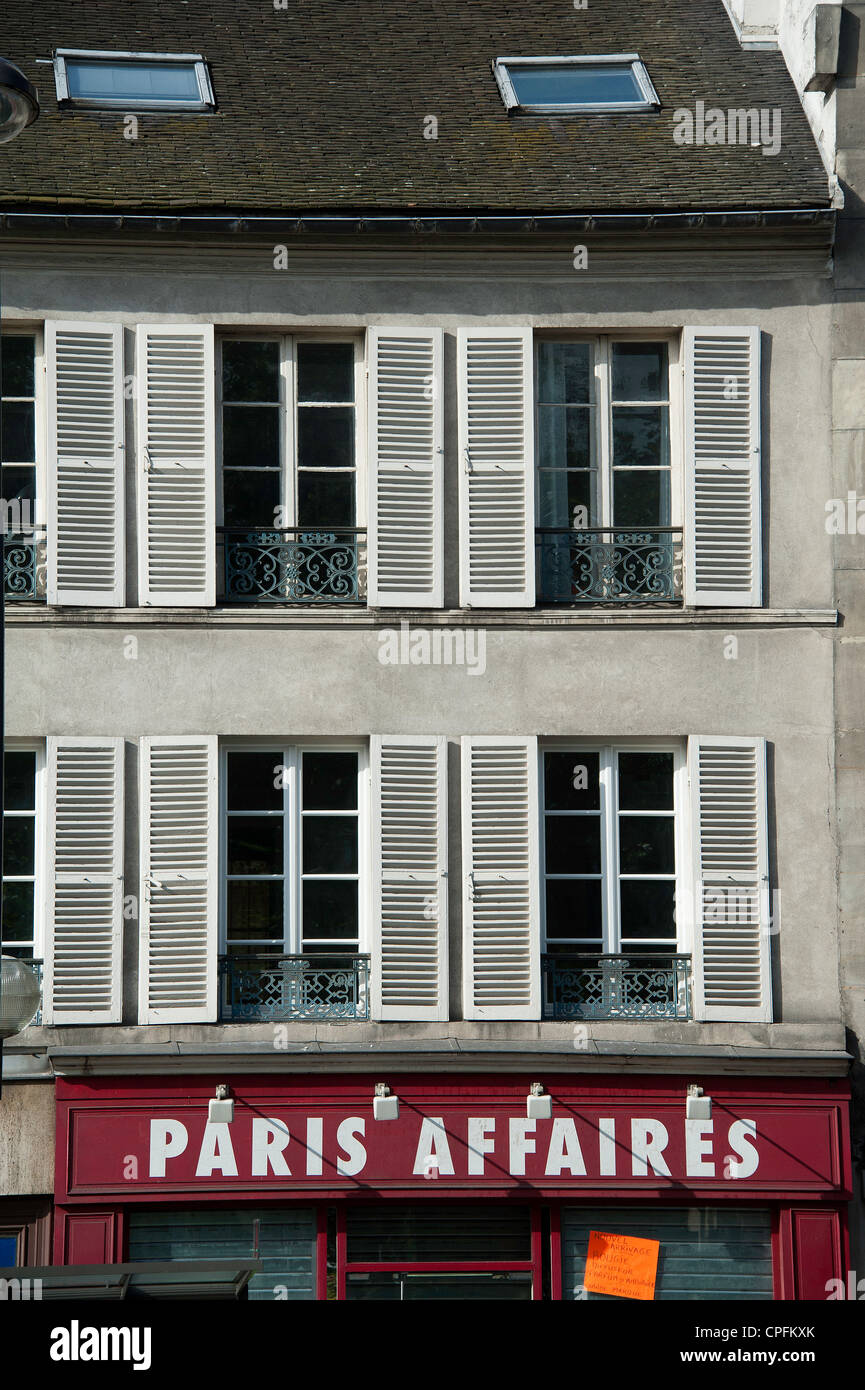 Shop in Paris with traditional shutters and wrought iron balcony Stock ...