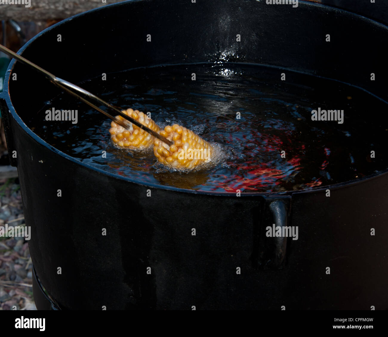 Cooking corn cobs in the pitchfork fondue Stock Photo - Alamy