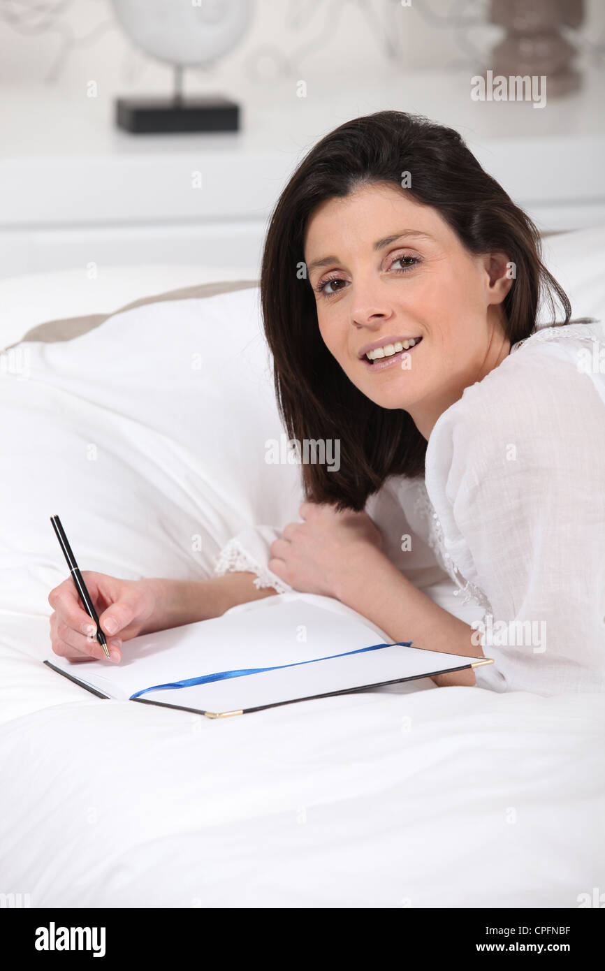 Brunette laying on her bed with diary Stock Photo - Alamy