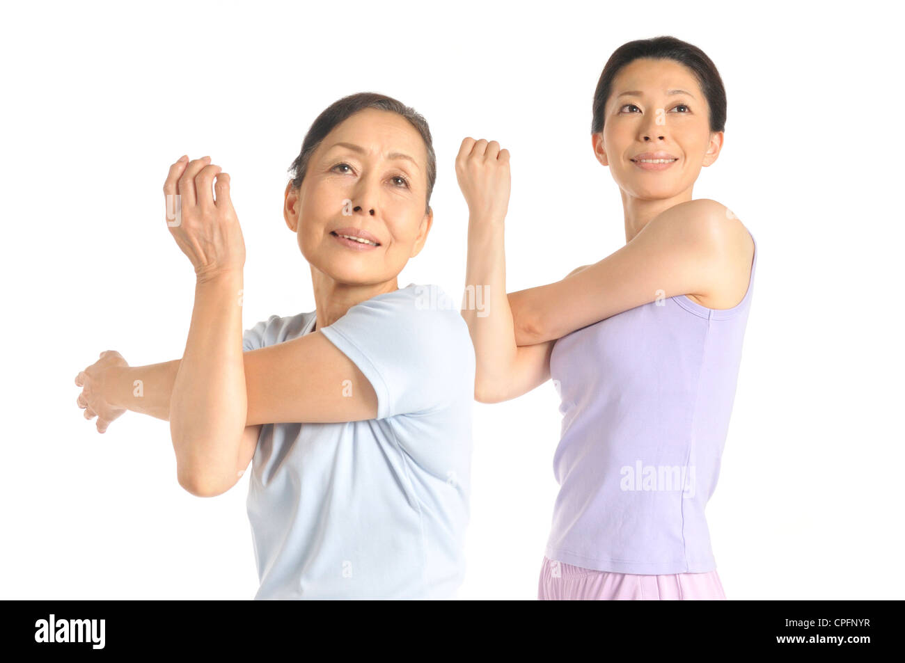 Senior woman and mid adult woman stretching upper arms Stock Photo - Alamy