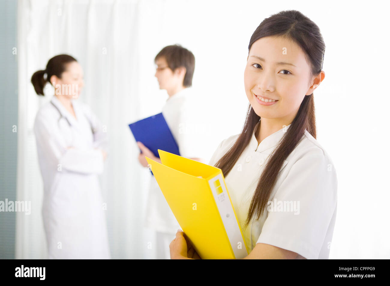 Female nurse smiling and holding file Stock Photo - Alamy