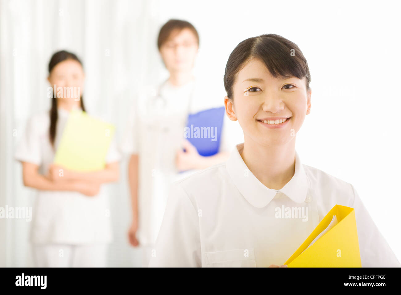 Female nurse smiling and holding file Stock Photo - Alamy