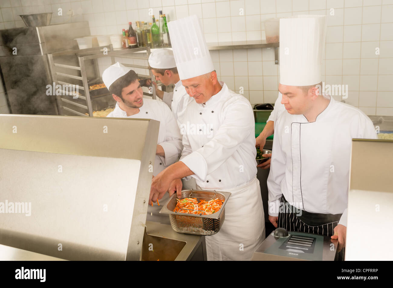 Professional chef cook with team prepare food in industrial kitchen ...