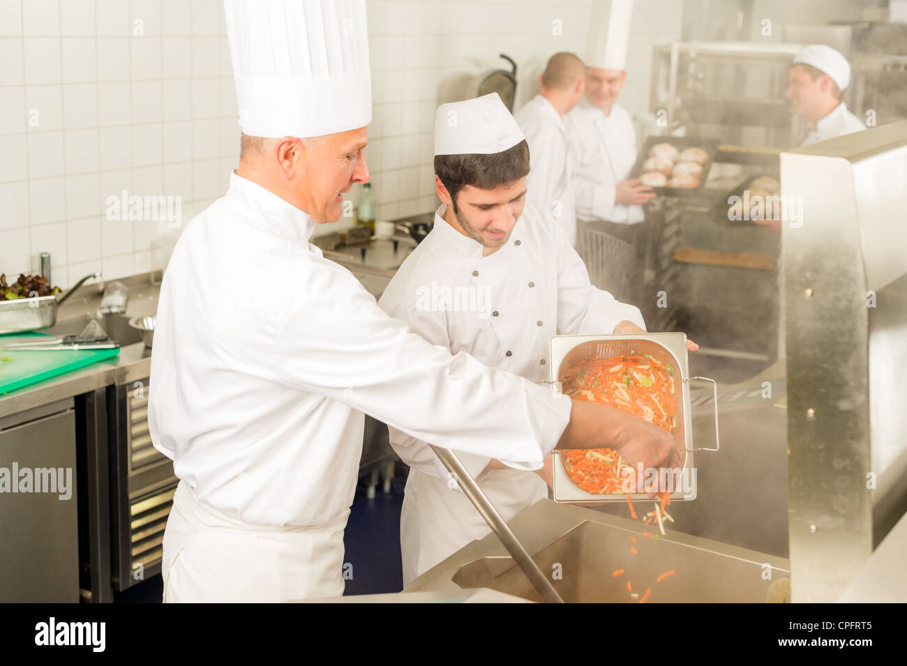 Professional chef cook with team prepare food in industrial kitchen ...