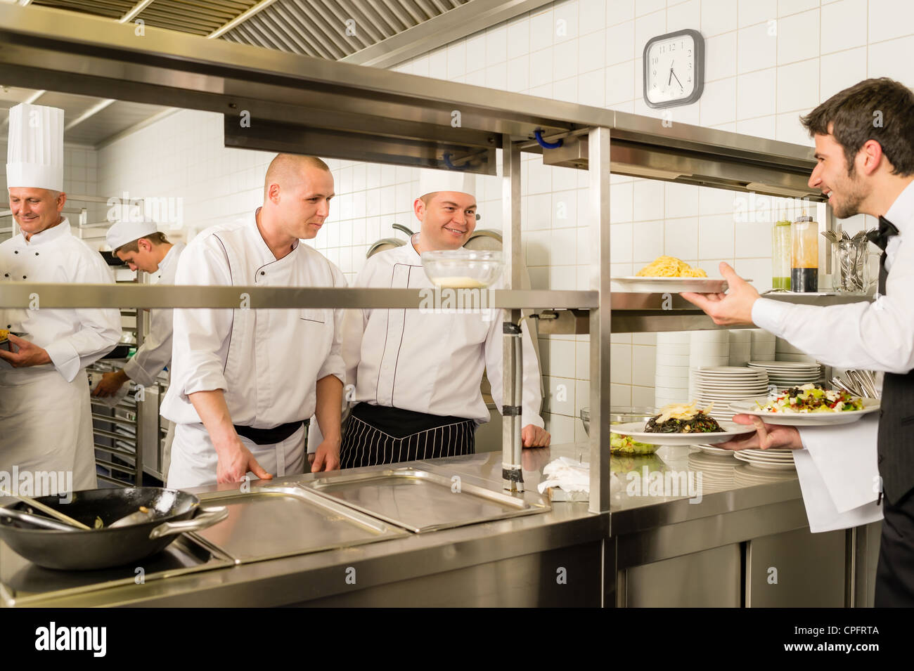 Restaurant waiter take meals from professional cook stainless kitchen ...