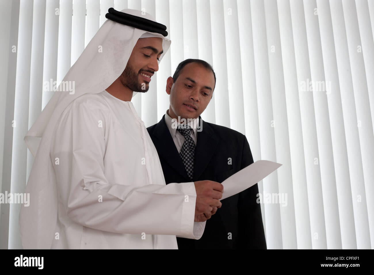 Two businessmen reading a document together in a conference room Stock ...