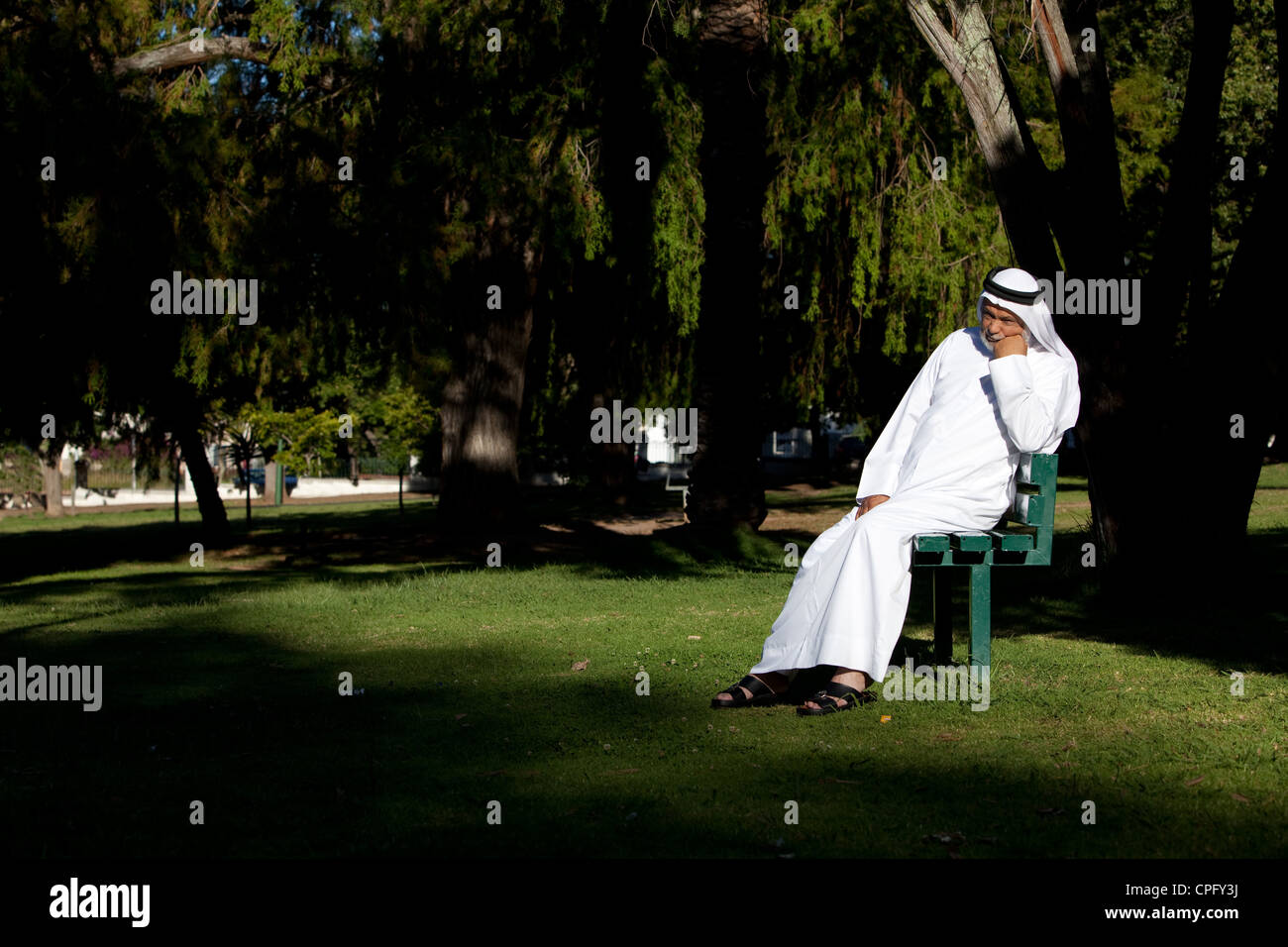 Senior arab man with hand on cheek sitting on bench at the park Stock ...