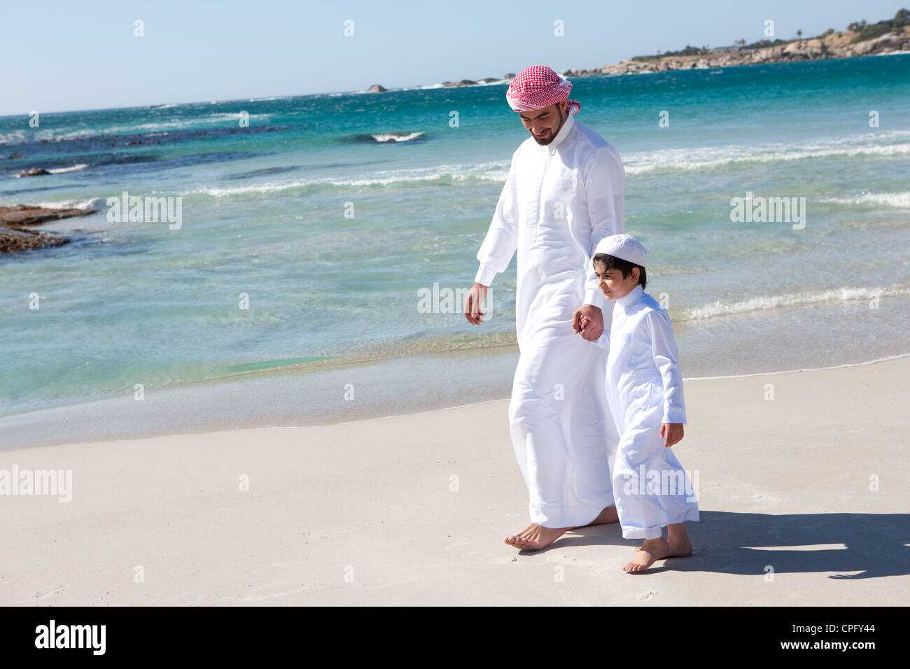 Arab father and son walking at the beach Stock Photo - Alamy
