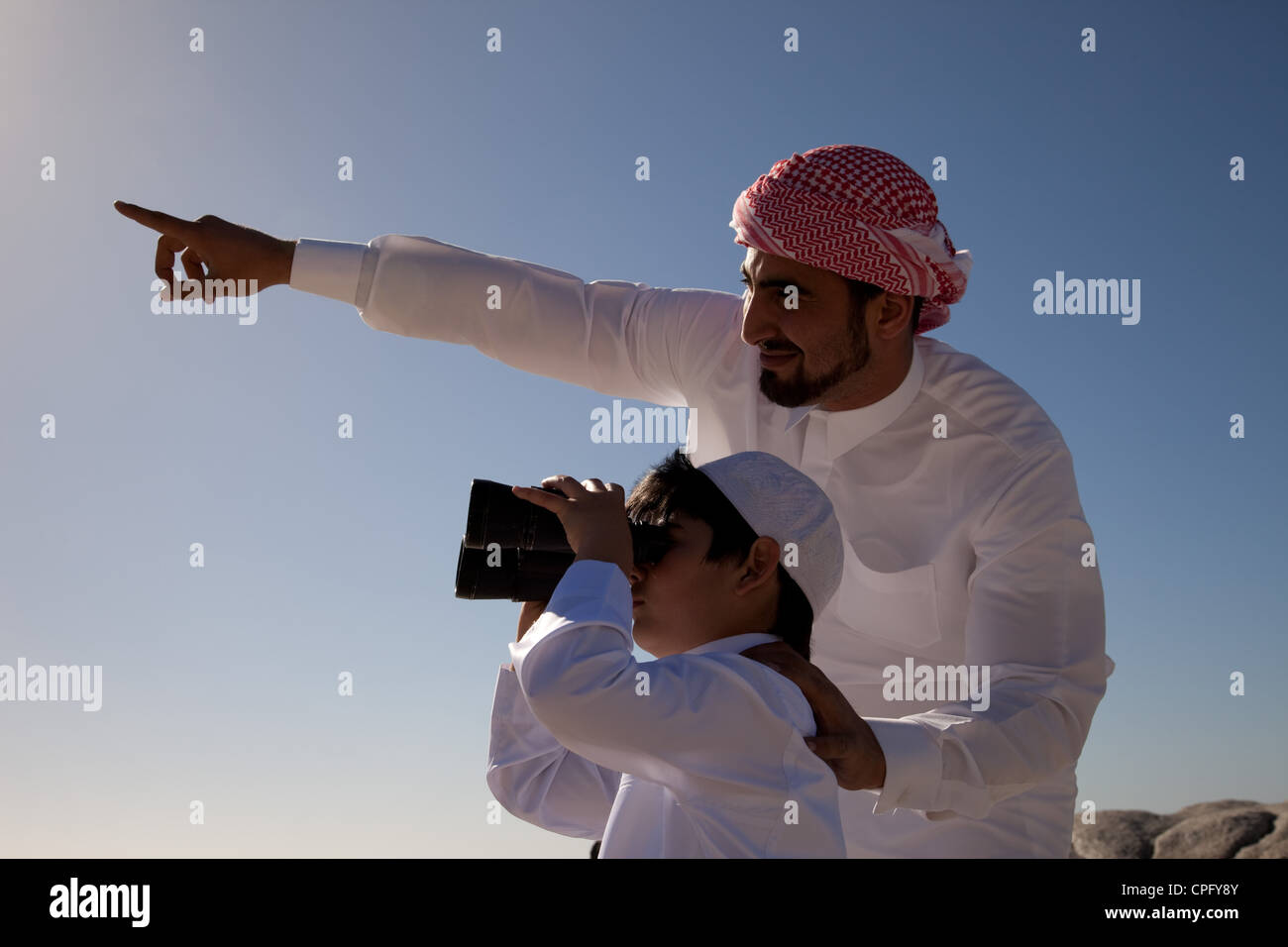 Arab father and son looking through binoculars by the beach Stock Photo ...