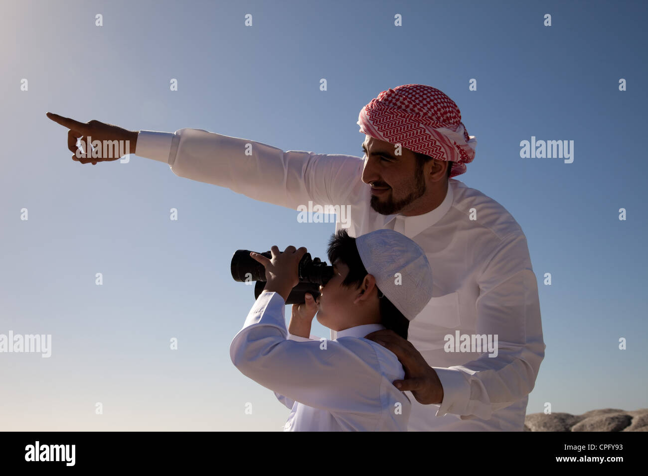 Arab father and son looking through binoculars by the beach Stock Photo ...