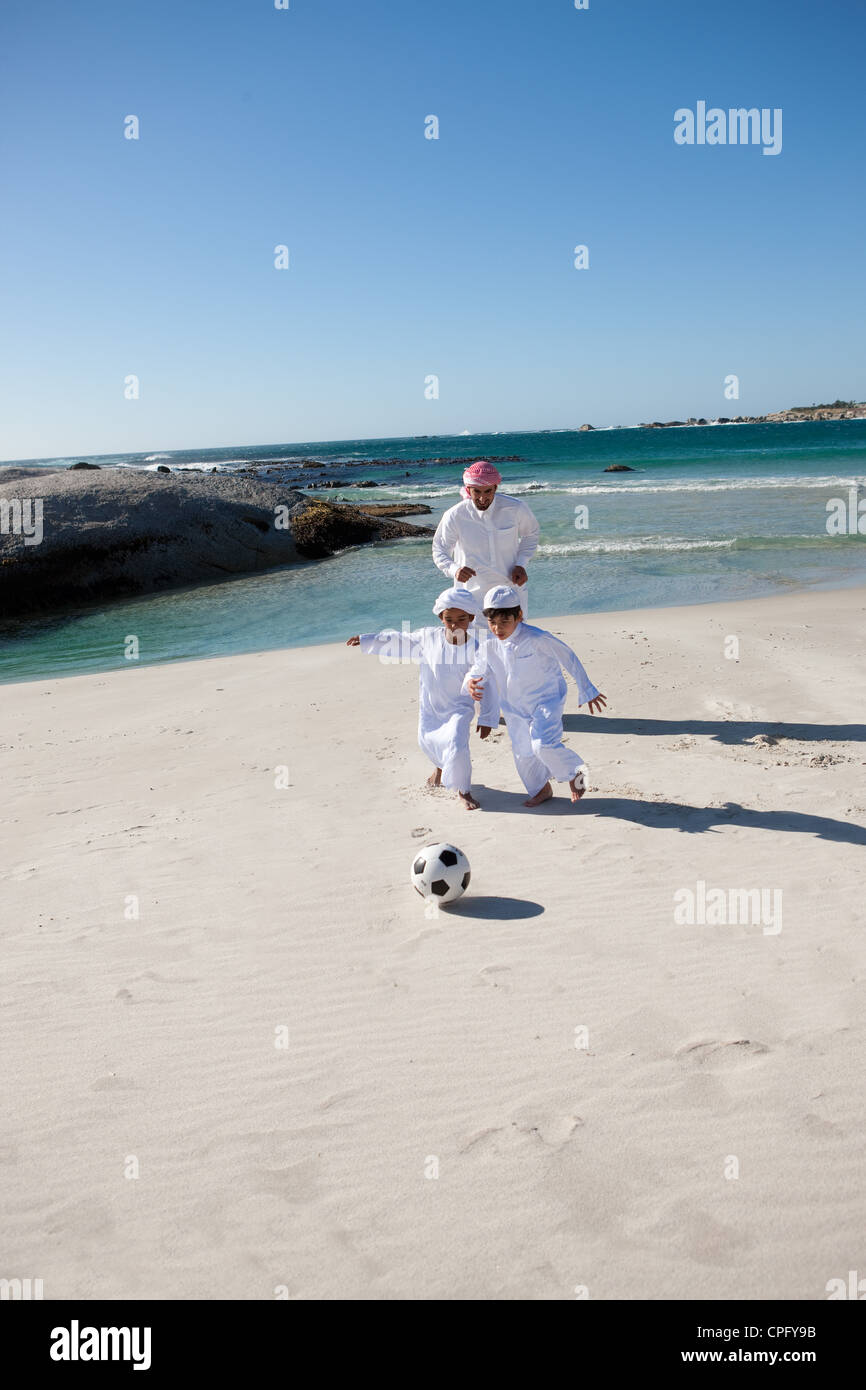 Arab father with two sons playing soccer ball by the beach Stock Photo ...