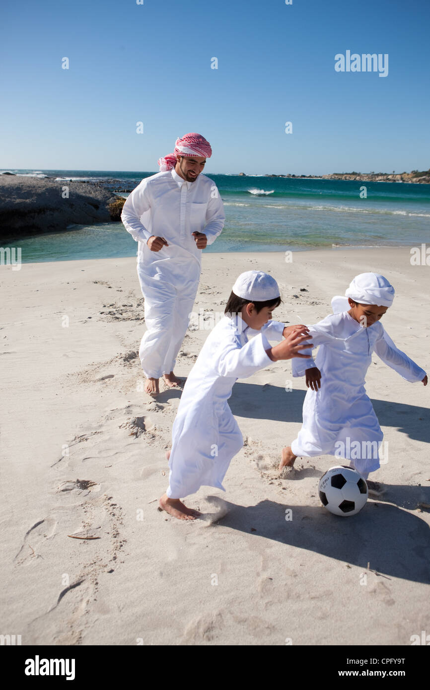 Arab father with two sons playing soccer ball by the beach Stock Photo ...