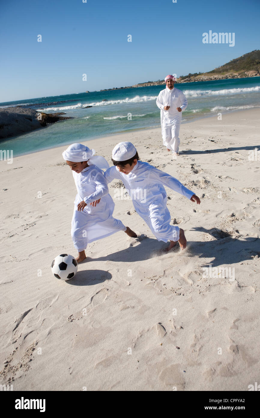 Arab father with two sons playing soccer ball by the beach Stock Photo ...