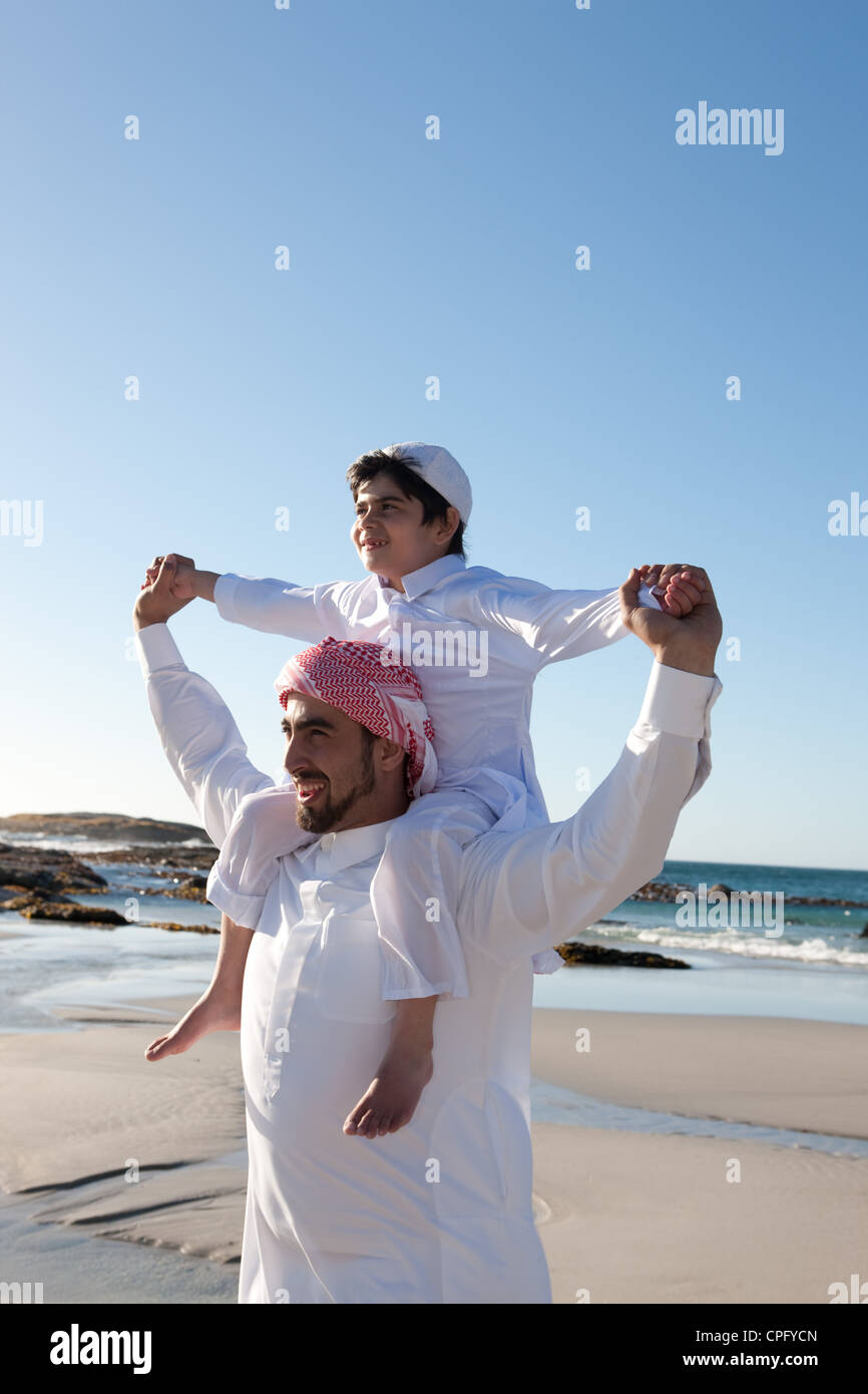 Arab father carrying his son on shoulders at the beach Stock Photo - Alamy
