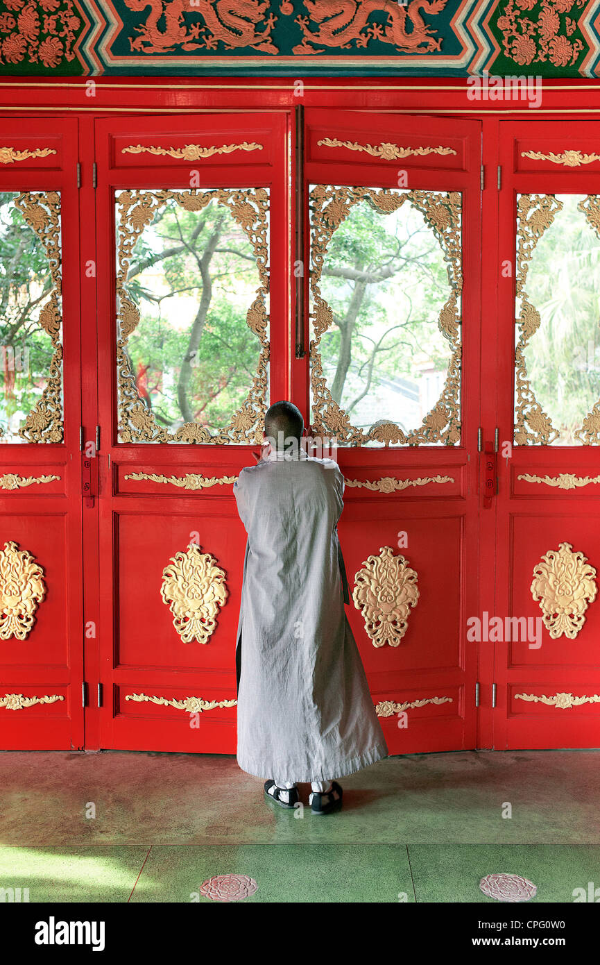 A monk adjusting the doors inside the Po Lin Monastery temple Stock ...