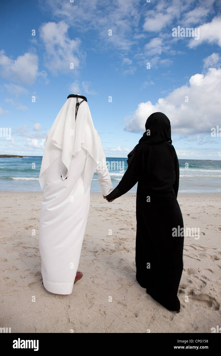Rear view of arab couple holding hands at the beach Stock Photo - Alamy