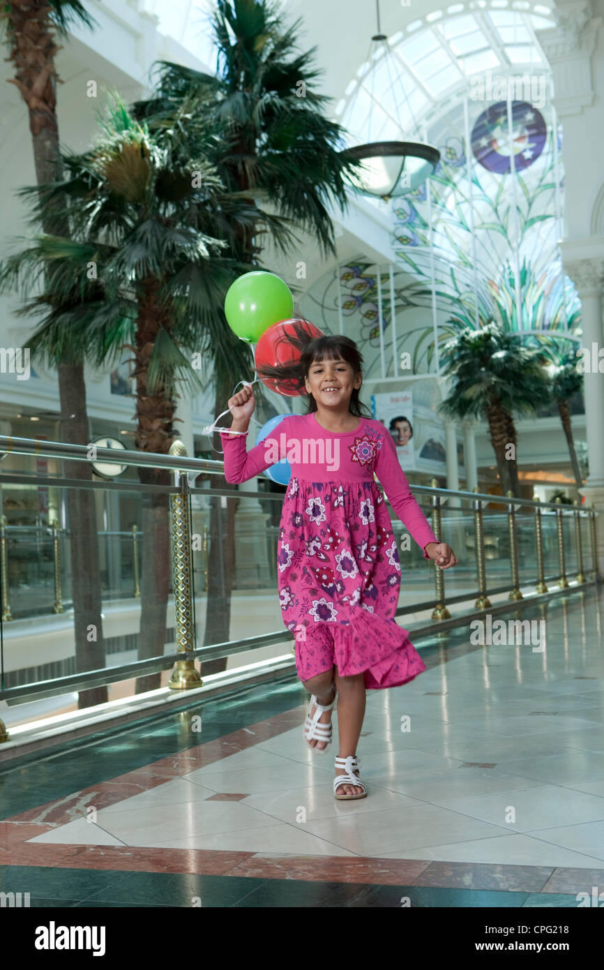 Girl running with balloons in the shopping mall Stock Photo - Alamy
