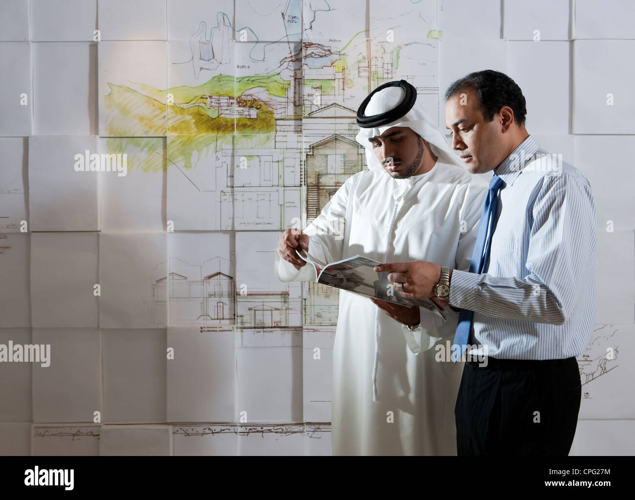 Two businessmen holding magazine, standing by the wall Stock Photo - Alamy