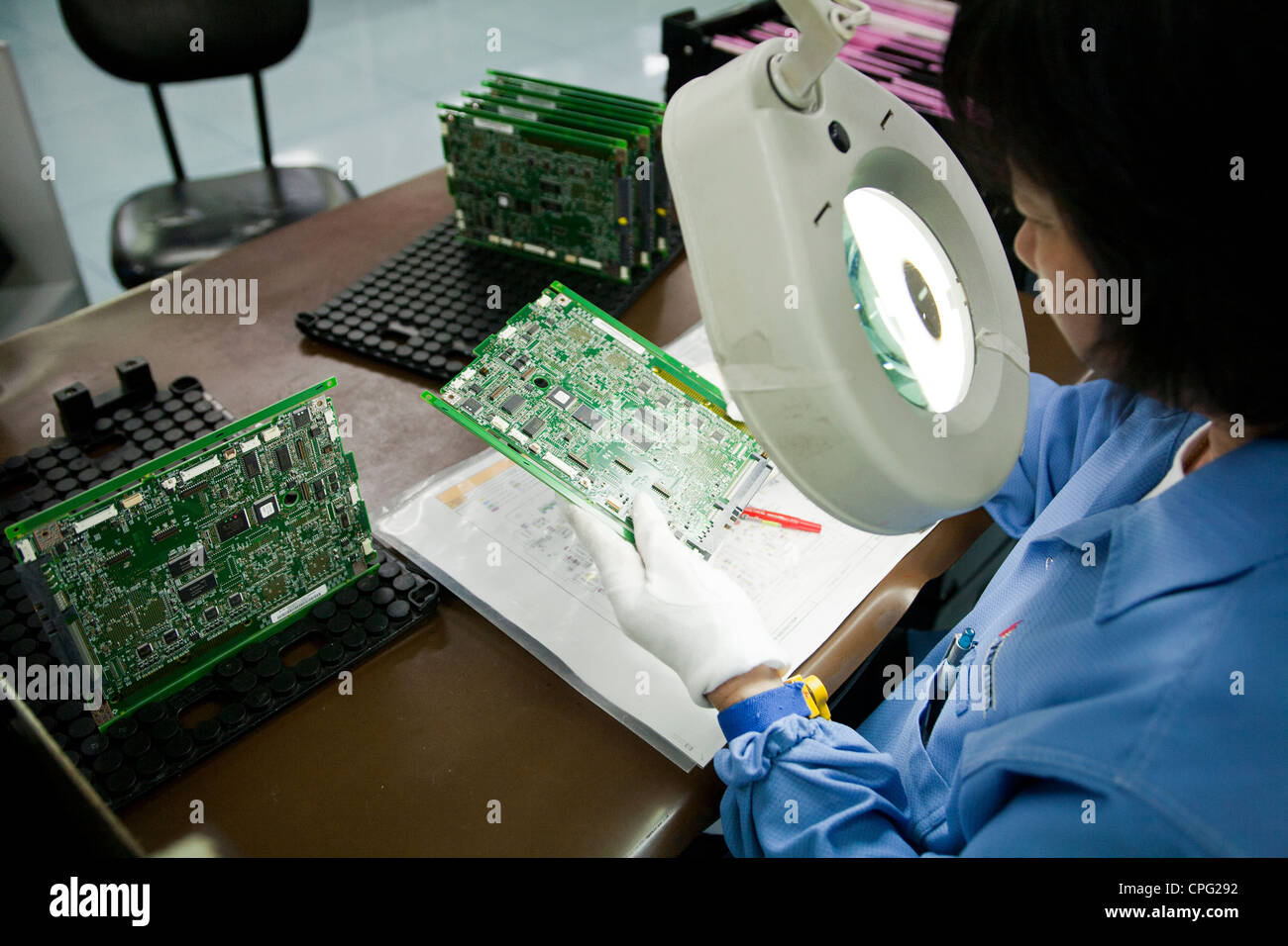 A worker inspects a printed circuit board on the assembly line at the ...