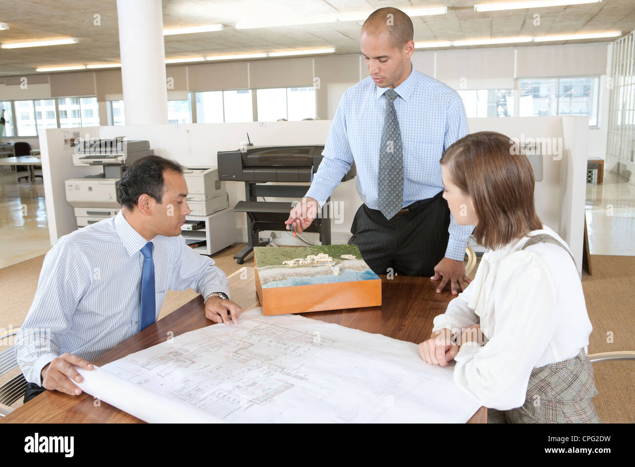 Three business people discussing over blueprint Stock Photo - Alamy