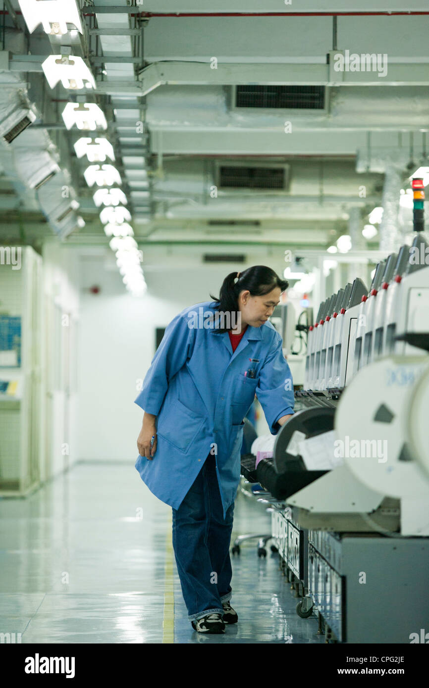 A worker checks machines on the assembly line at the Venture Corp ...