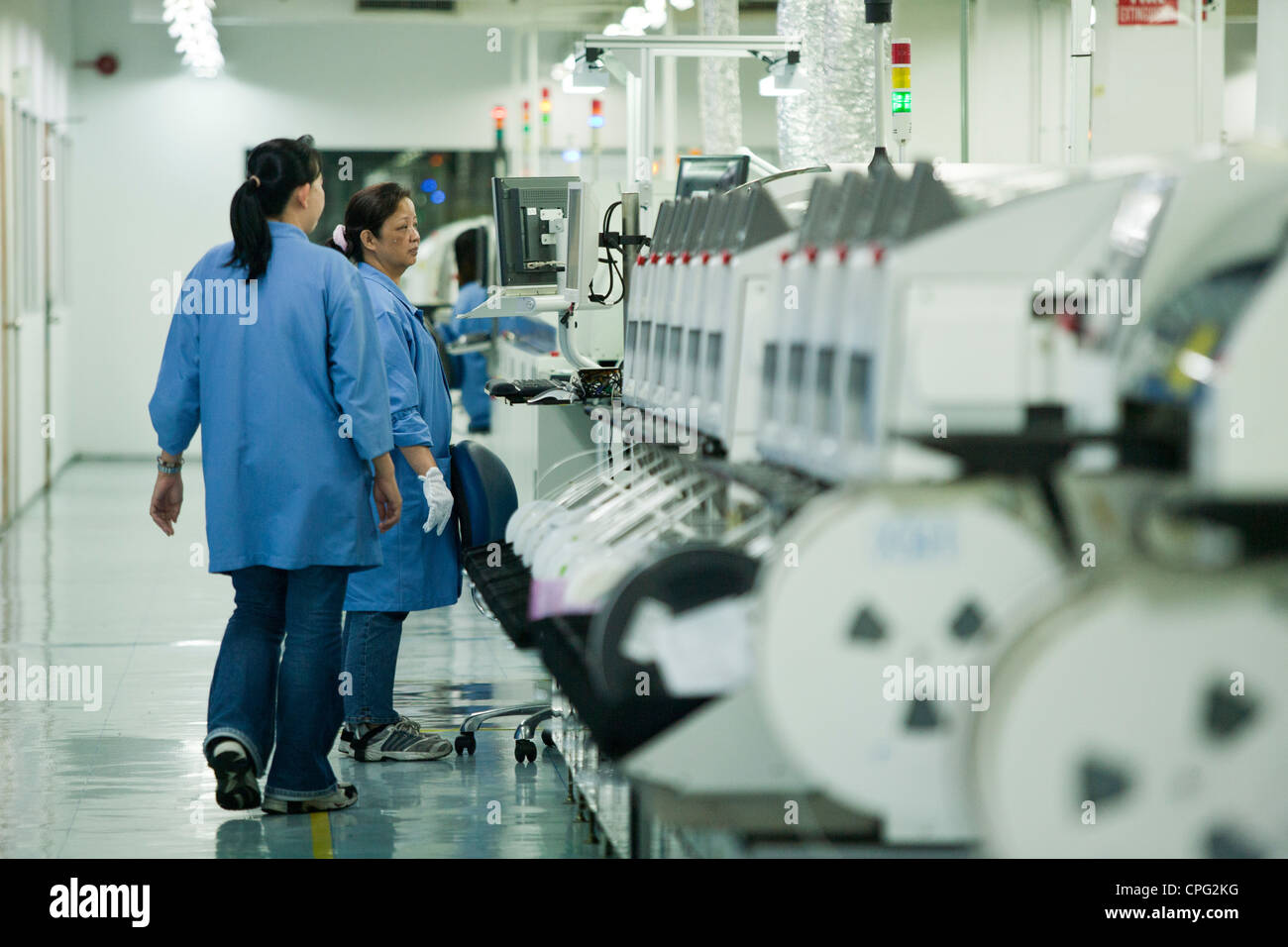 Workers check machines on the assembly line at the Venture Corp ...