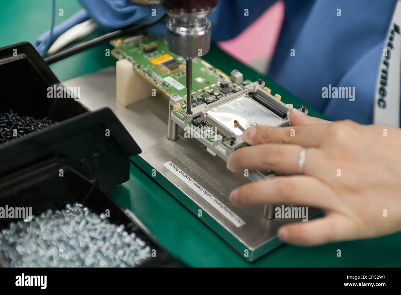 A worker assembles hand-held inventory computer devices on the assembly ...