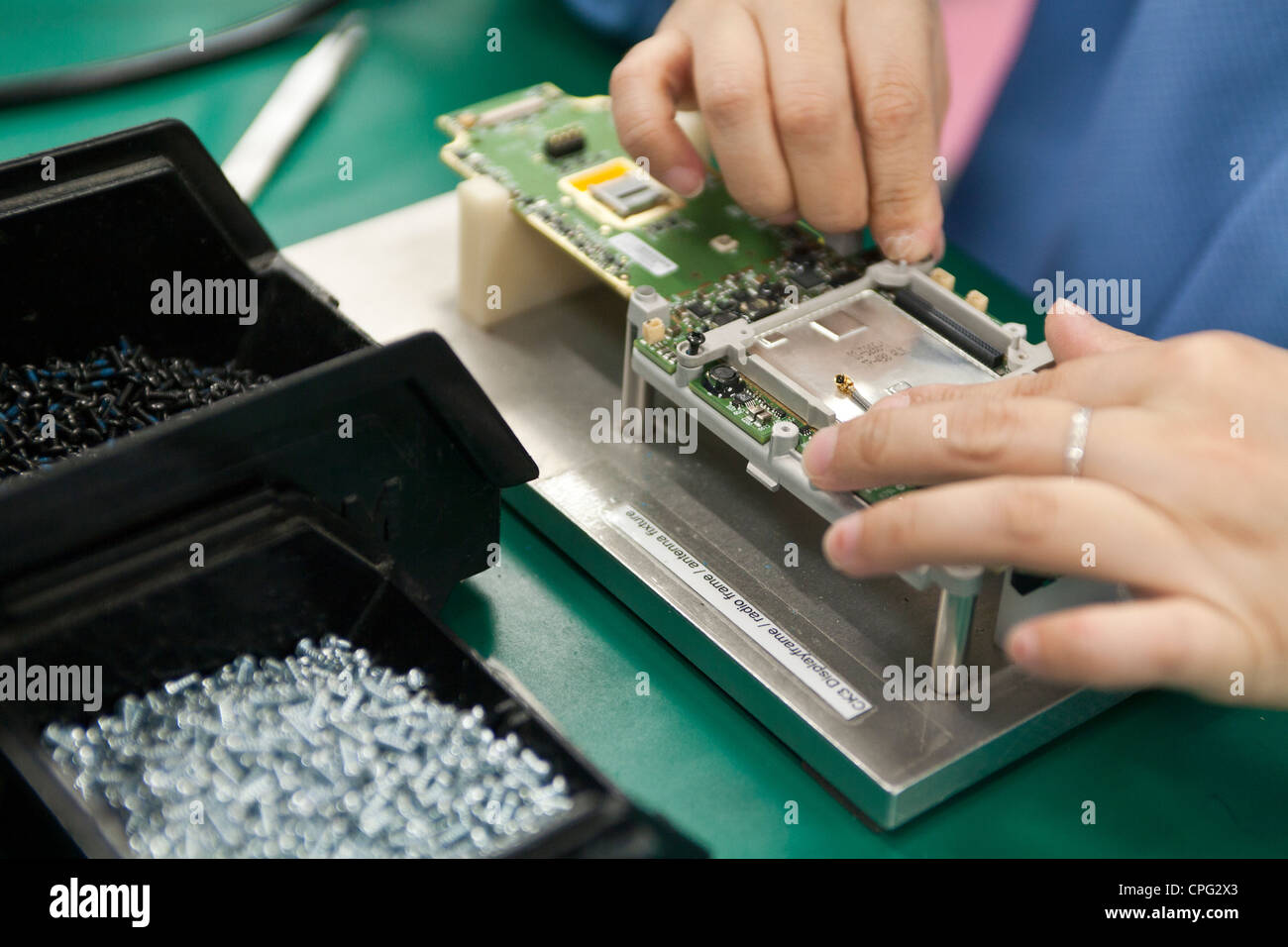 A worker assembles hand-held inventory computer devices on the assembly ...