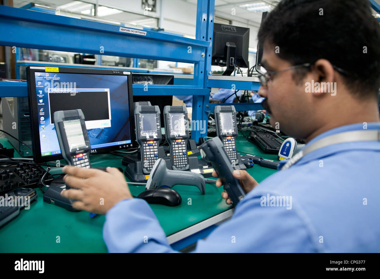 A worker tests hand-held inventory computer devices on the assembly ...