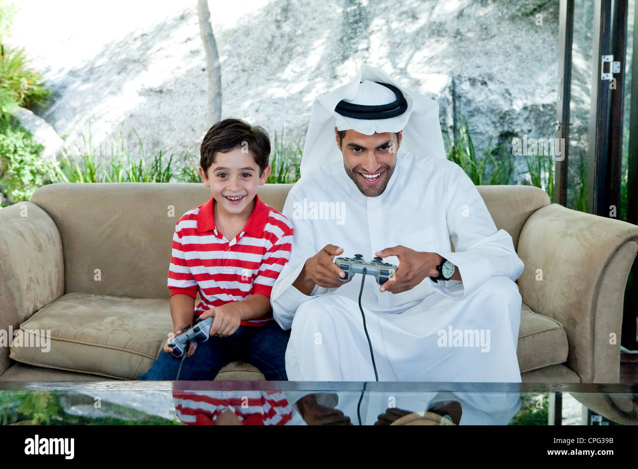 Arab father and son playing video game together Stock Photo - Alamy