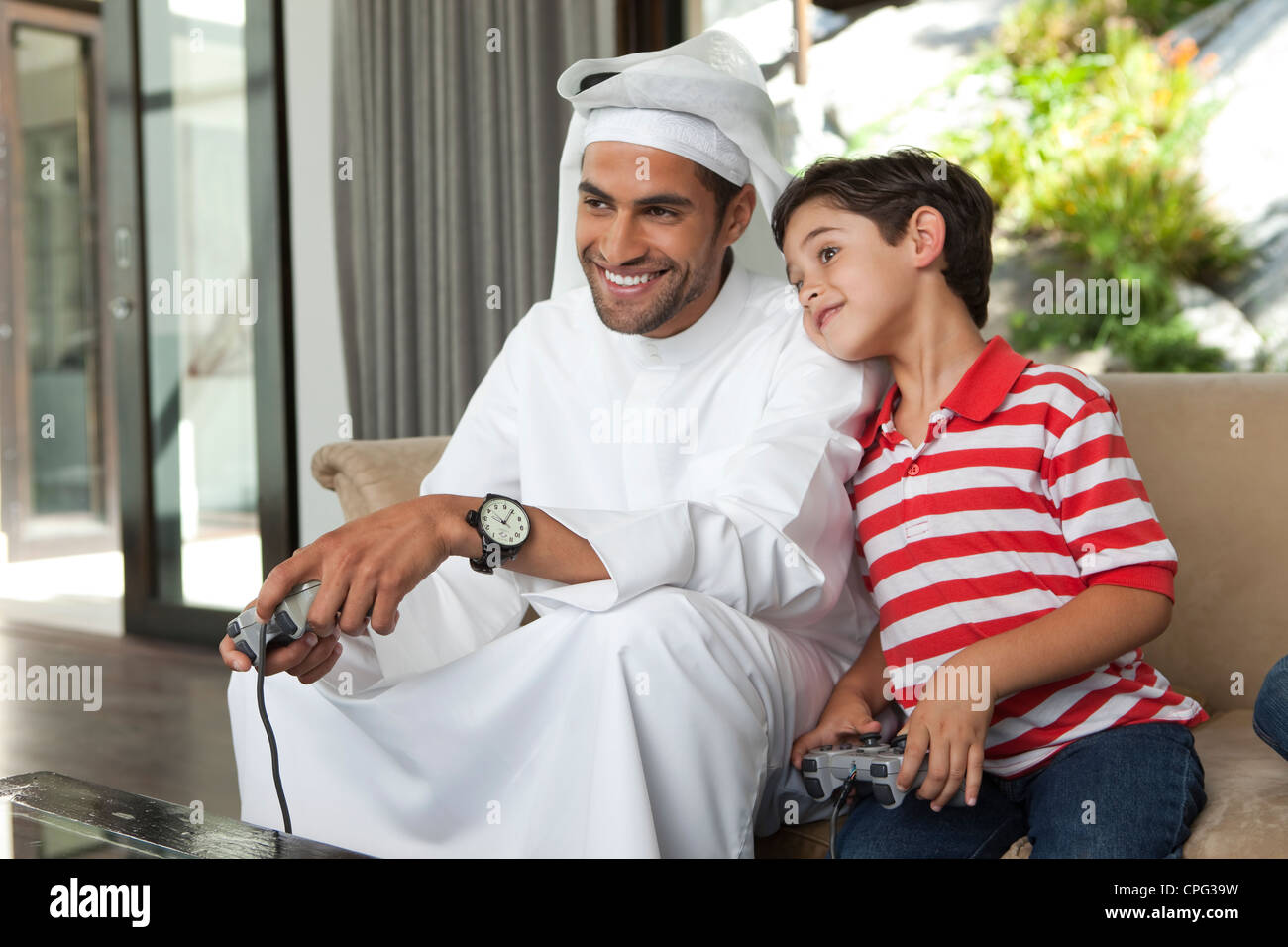 Arab father and son playing video game together Stock Photo - Alamy