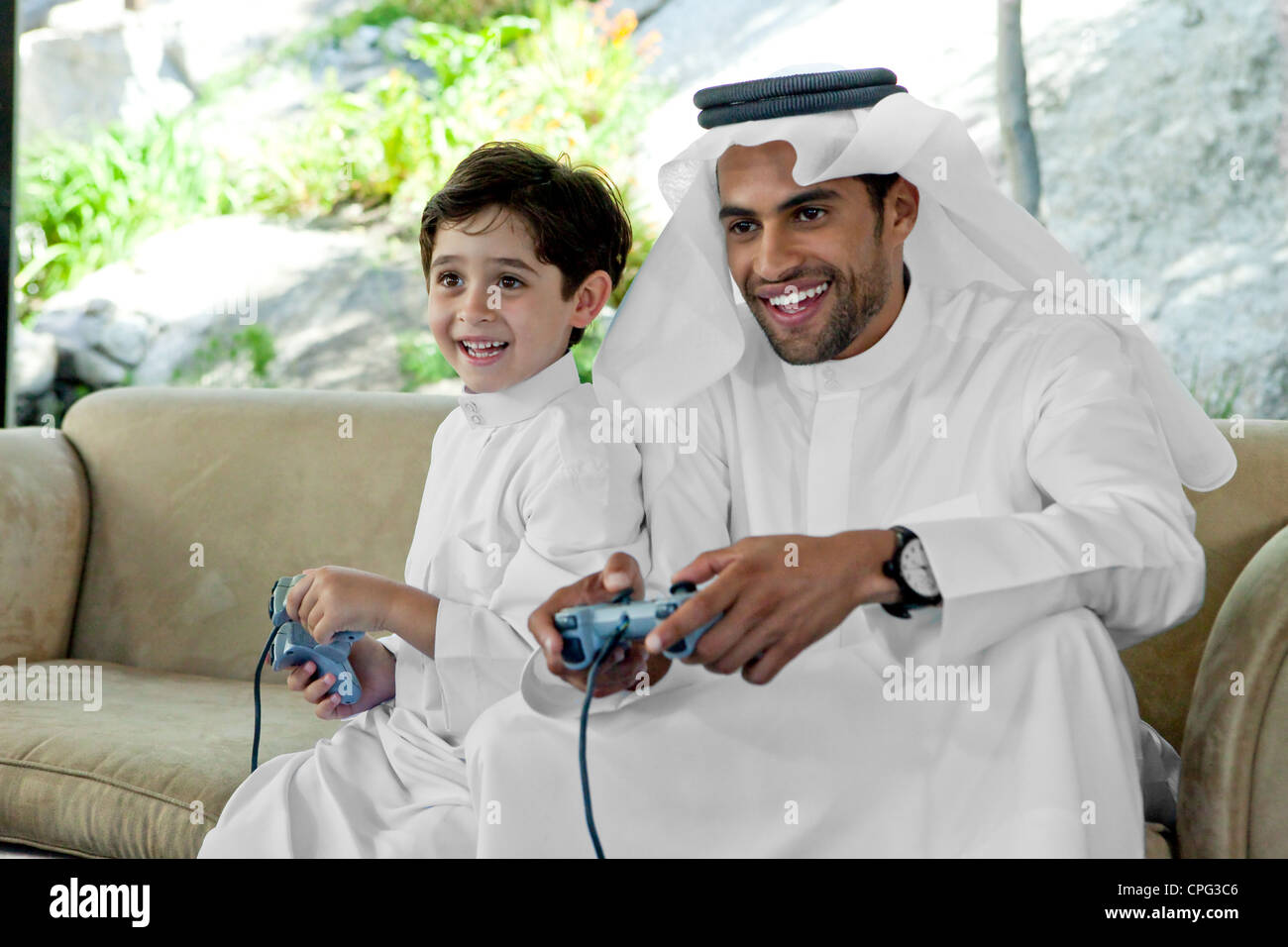 Arab father and son playing video game together Stock Photo - Alamy