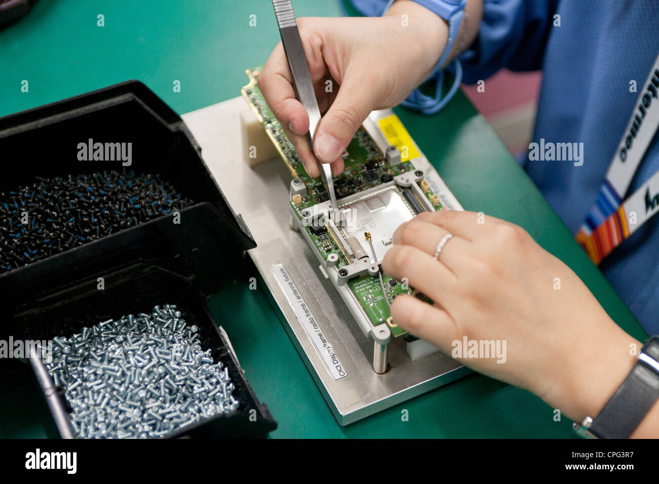 A worker assembles hand-held inventory computer devices on the assembly ...