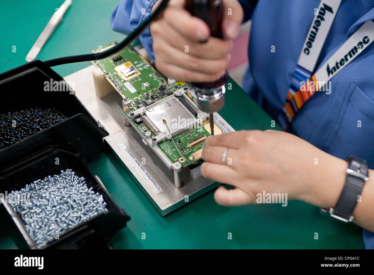 A worker assembles hand-held inventory computer devices on the assembly ...