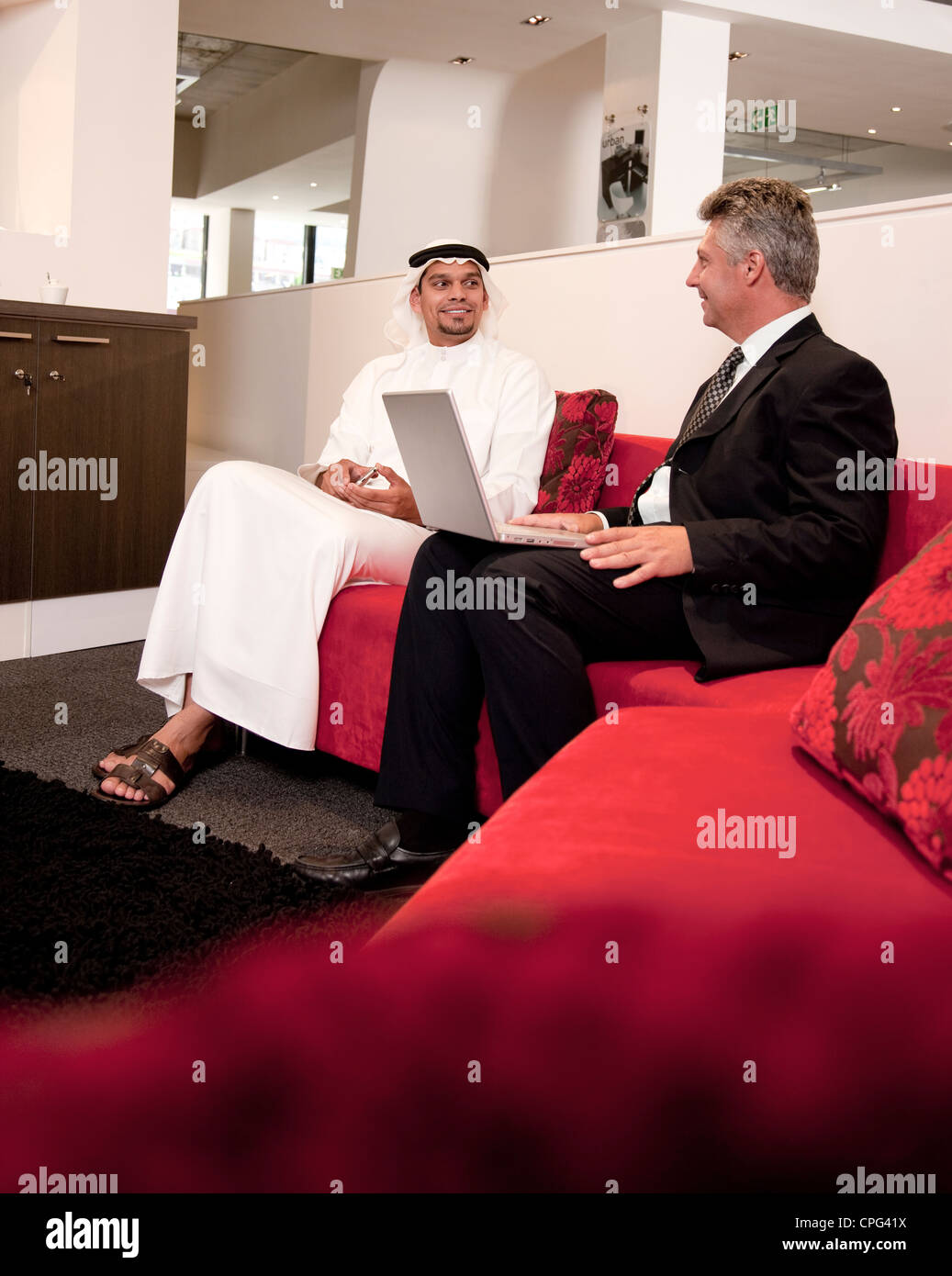 Two businessmen talking on sofa in office Stock Photo - Alamy