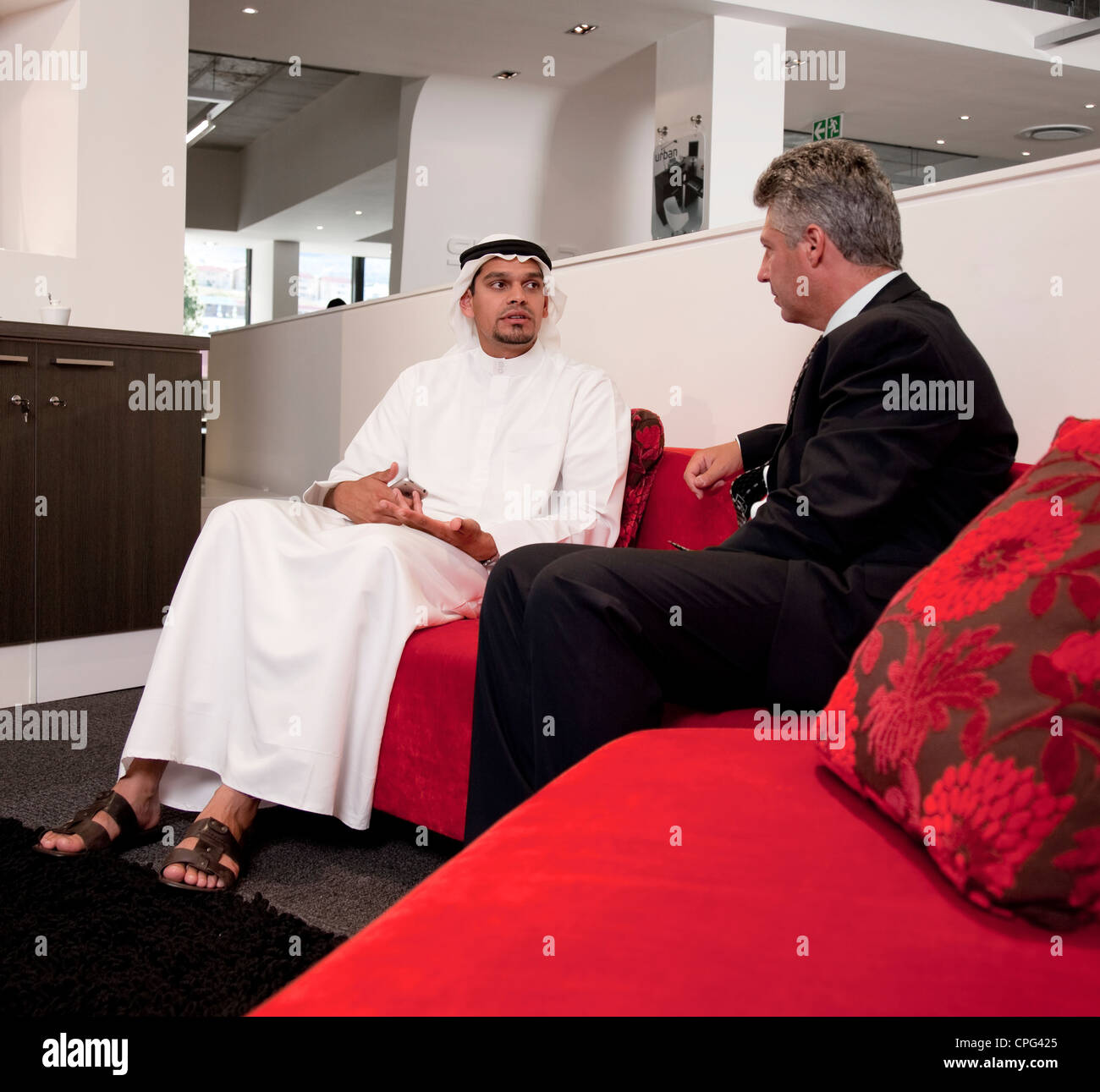 Two businessmen talking on sofa in office Stock Photo - Alamy