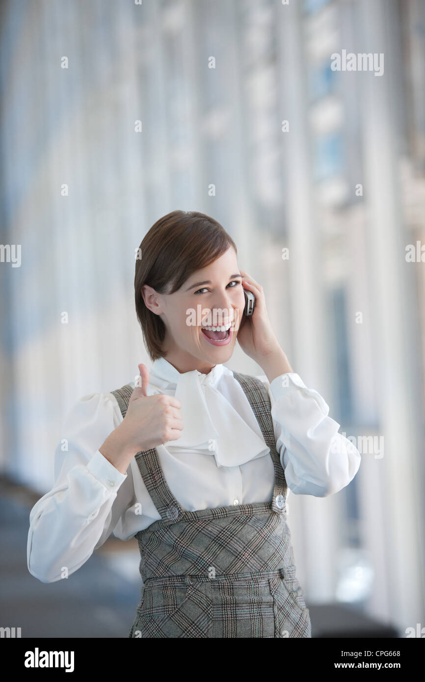 Businesswoman with mobile phone giving thumbs up Stock Photo - Alamy