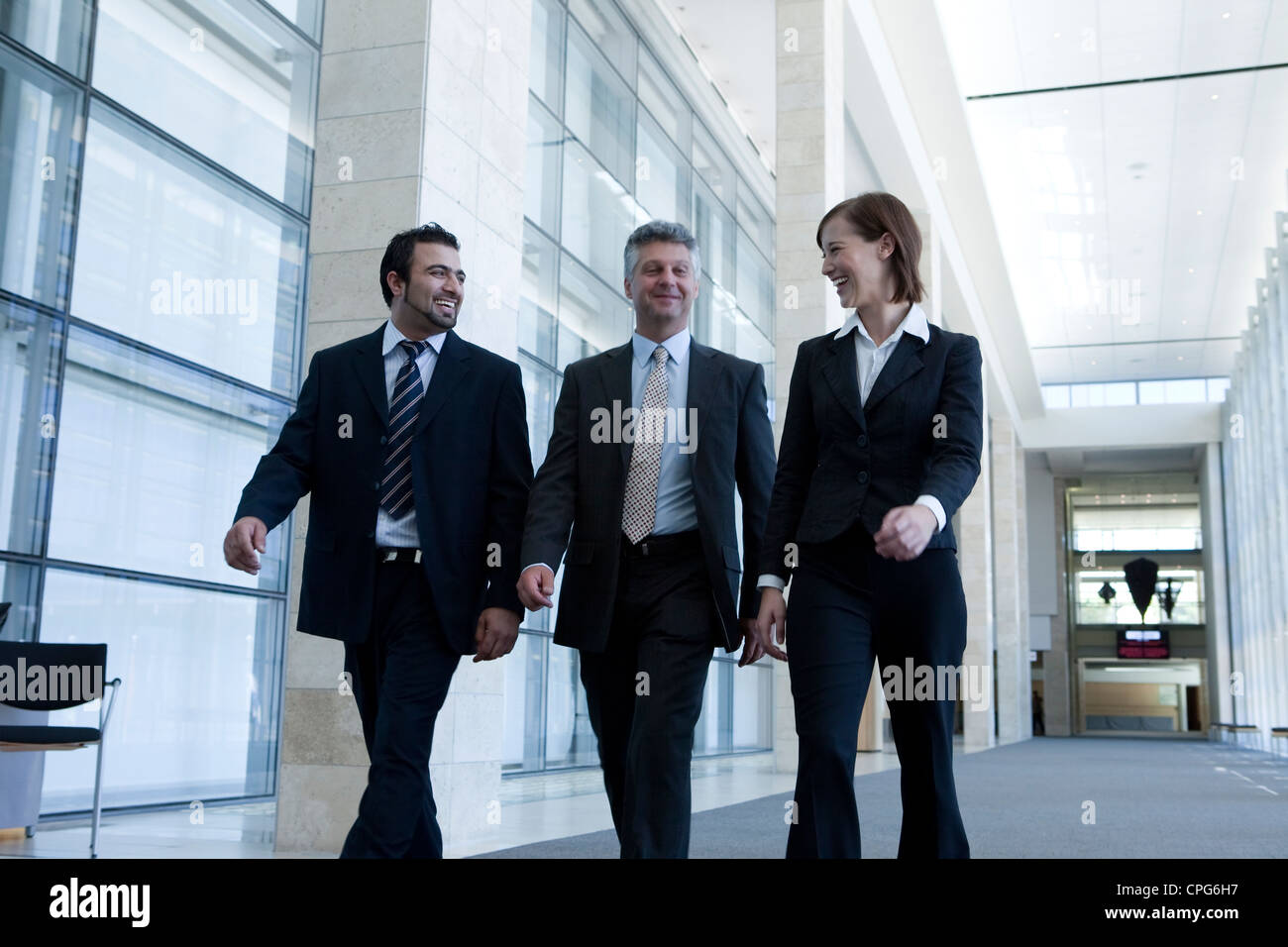 Three business people walking at the office hallway Stock Photo - Alamy