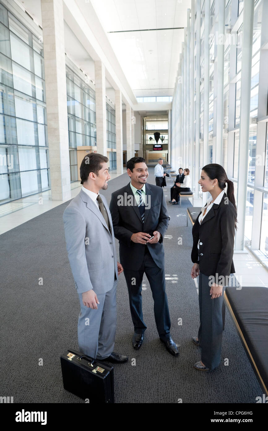 Three business people talking in the office hallway Stock Photo - Alamy