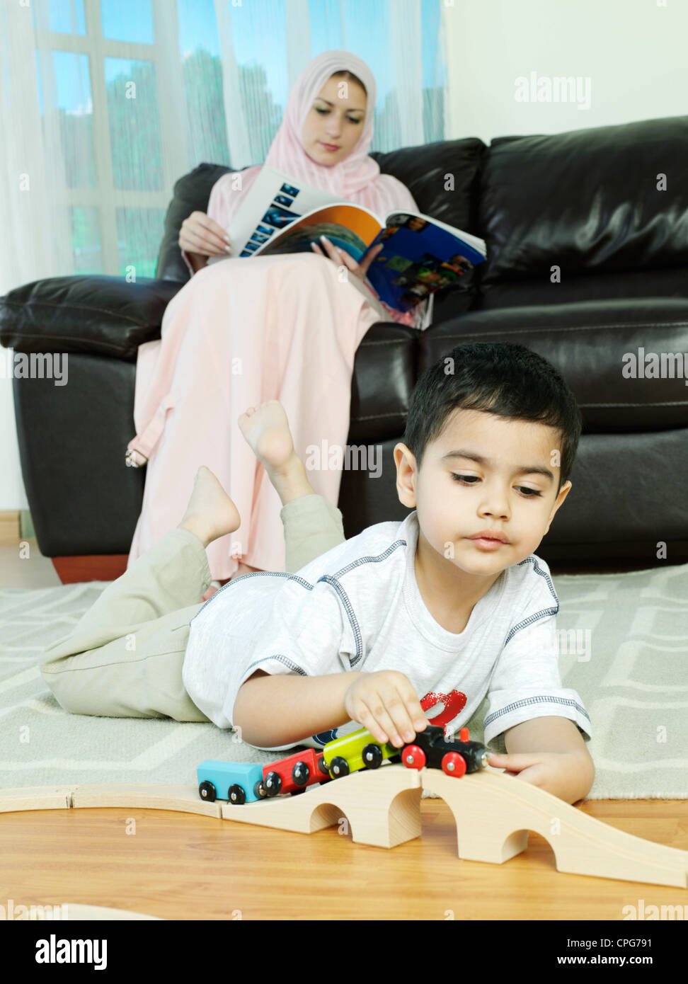 Kids are playing while Mother read the magazine Stock Photo - Alamy