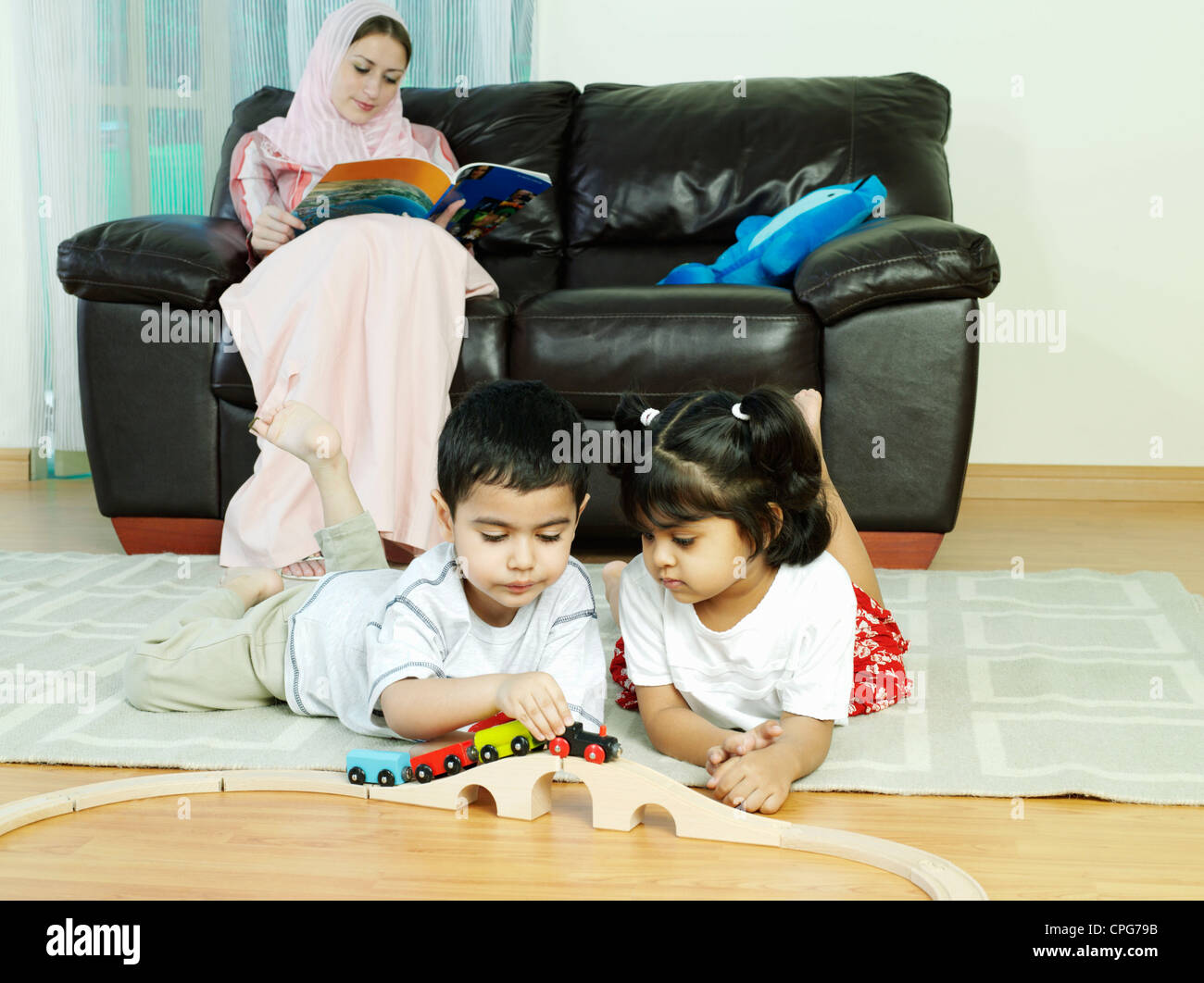 kids are playing while mother read the magazine Stock Photo - Alamy