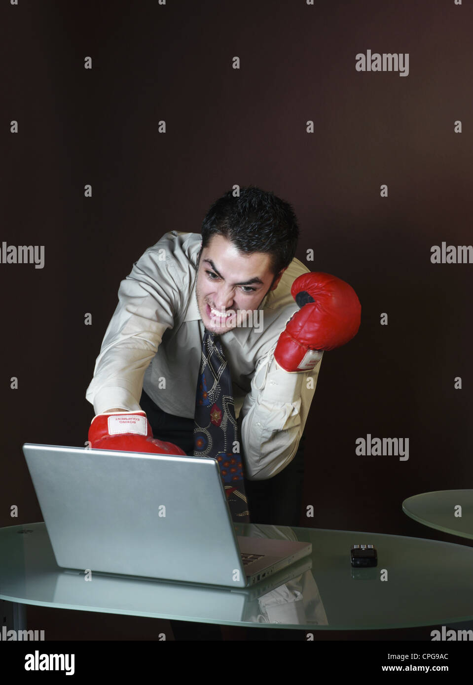 Young Businessman with boxing gloves attacking computer Stock Photo - Alamy