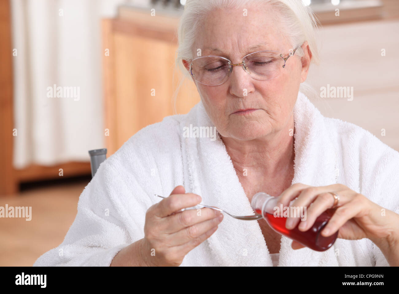 Senior woman taking cough syrup Stock Photo - Alamy