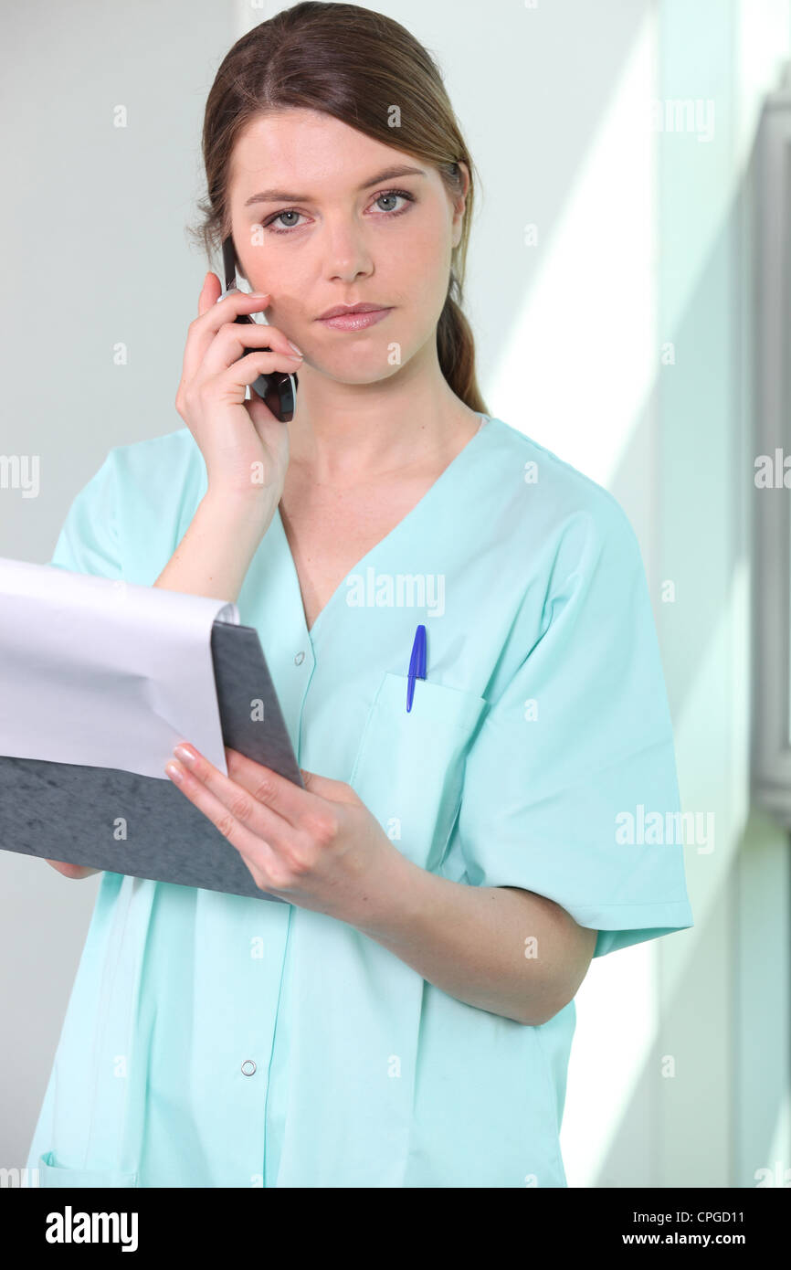 Brunette nurse, holding chart and mobile telephone Stock Photo - Alamy