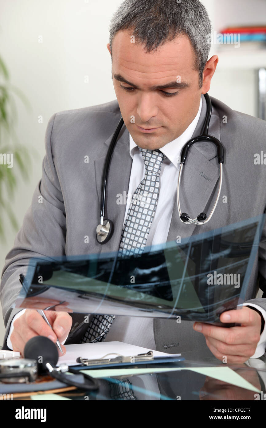 Doctor taking written notes whilst examining x-ray image Stock Photo ...