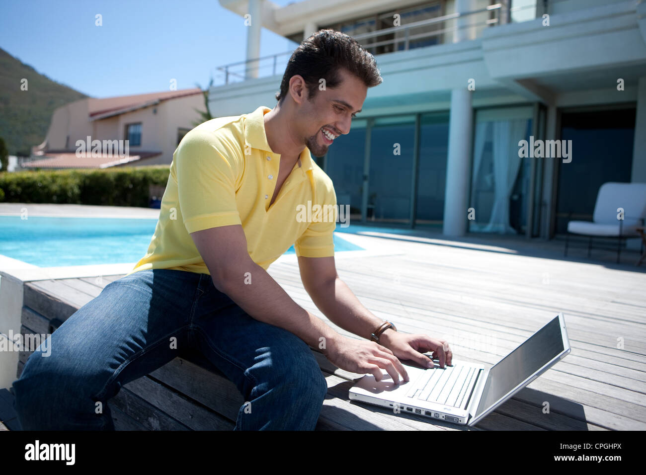 Man with laptop sitting by the swimming pool Stock Photo - Alamy